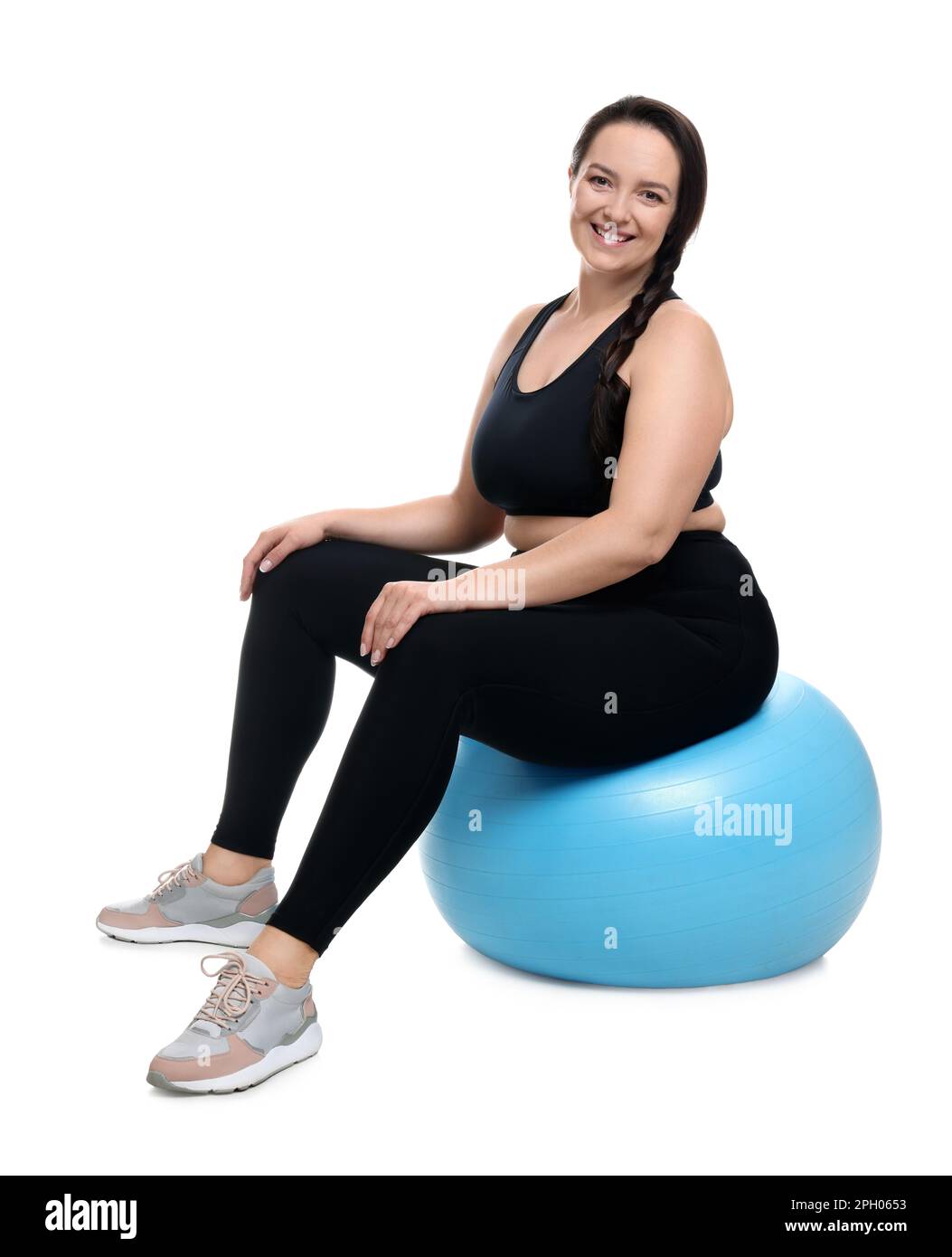 Happy overweight woman sitting on fitness ball against white background ...