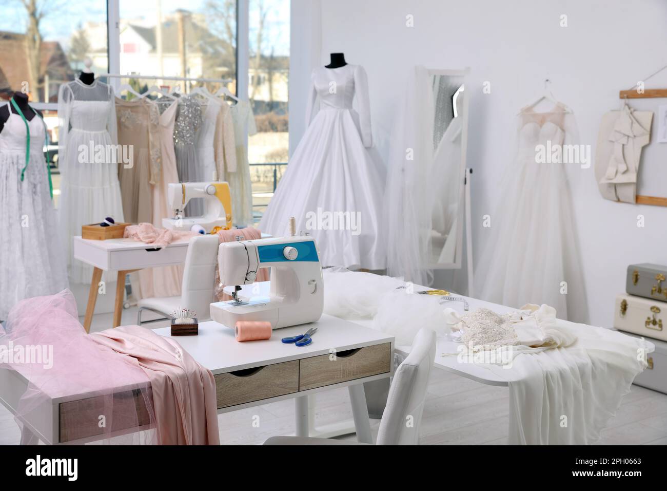Dressmaking workshop interior with wedding dresses and equipment Stock ...
