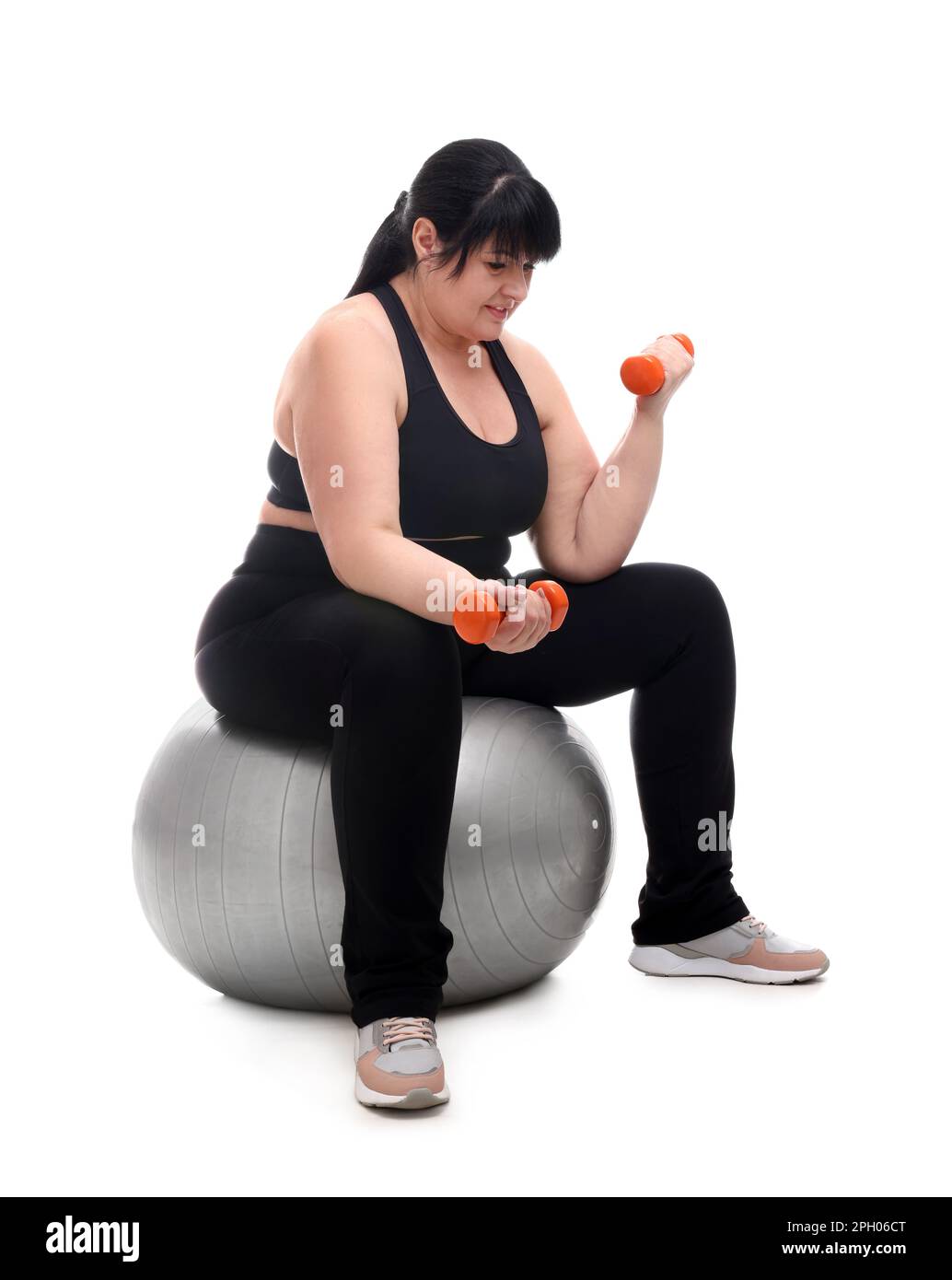 Happy overweight mature woman with dumbbells sitting on fitness ball ...