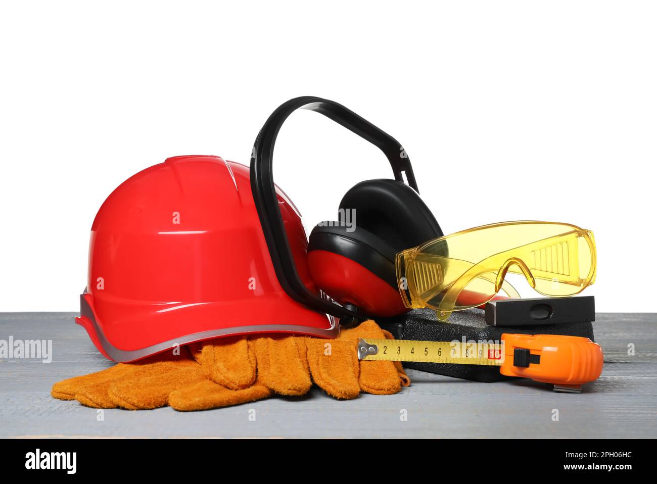 Set with safety equipment and tools on wooden table against white ...