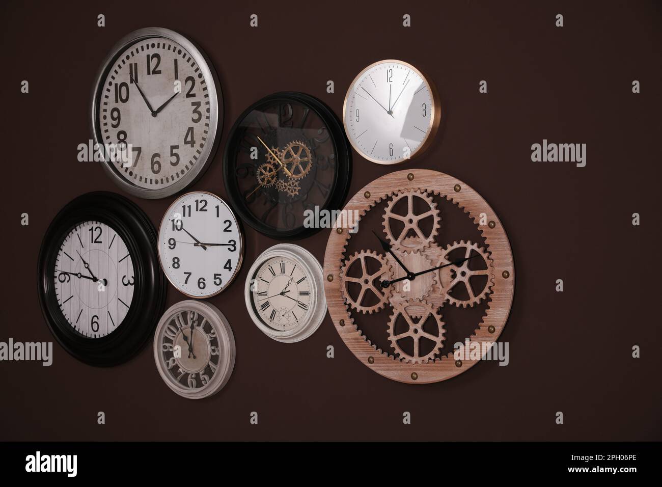 Collection of stylish clocks on brown wall Stock Photo - Alamy