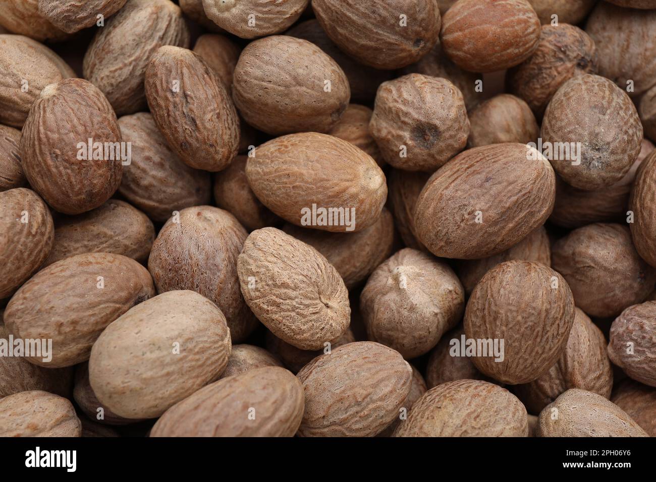 Heap of nutmeg seeds as background, top view Stock Photo - Alamy