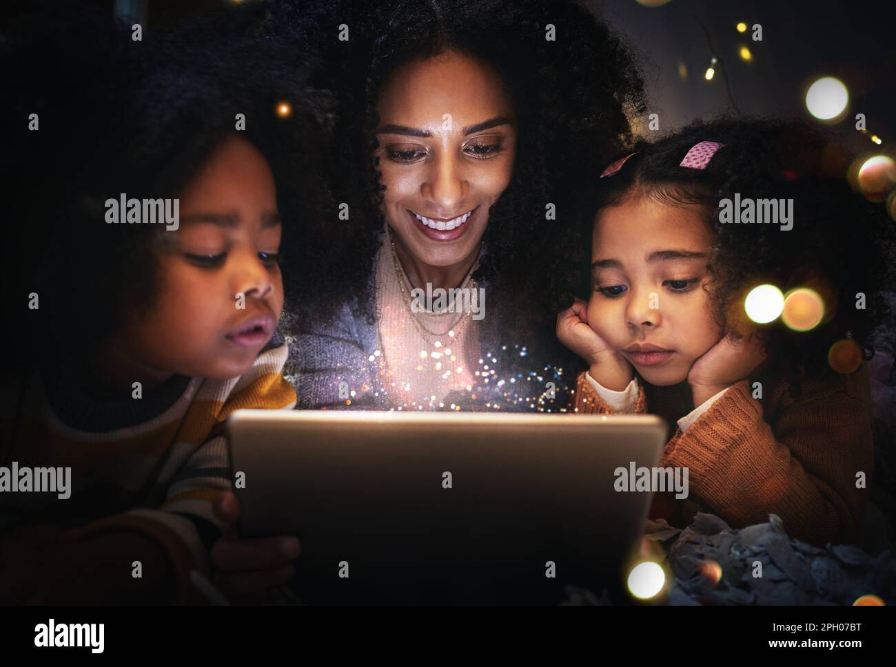 Tablet, night a woman reading to her children in a tent while camping ...