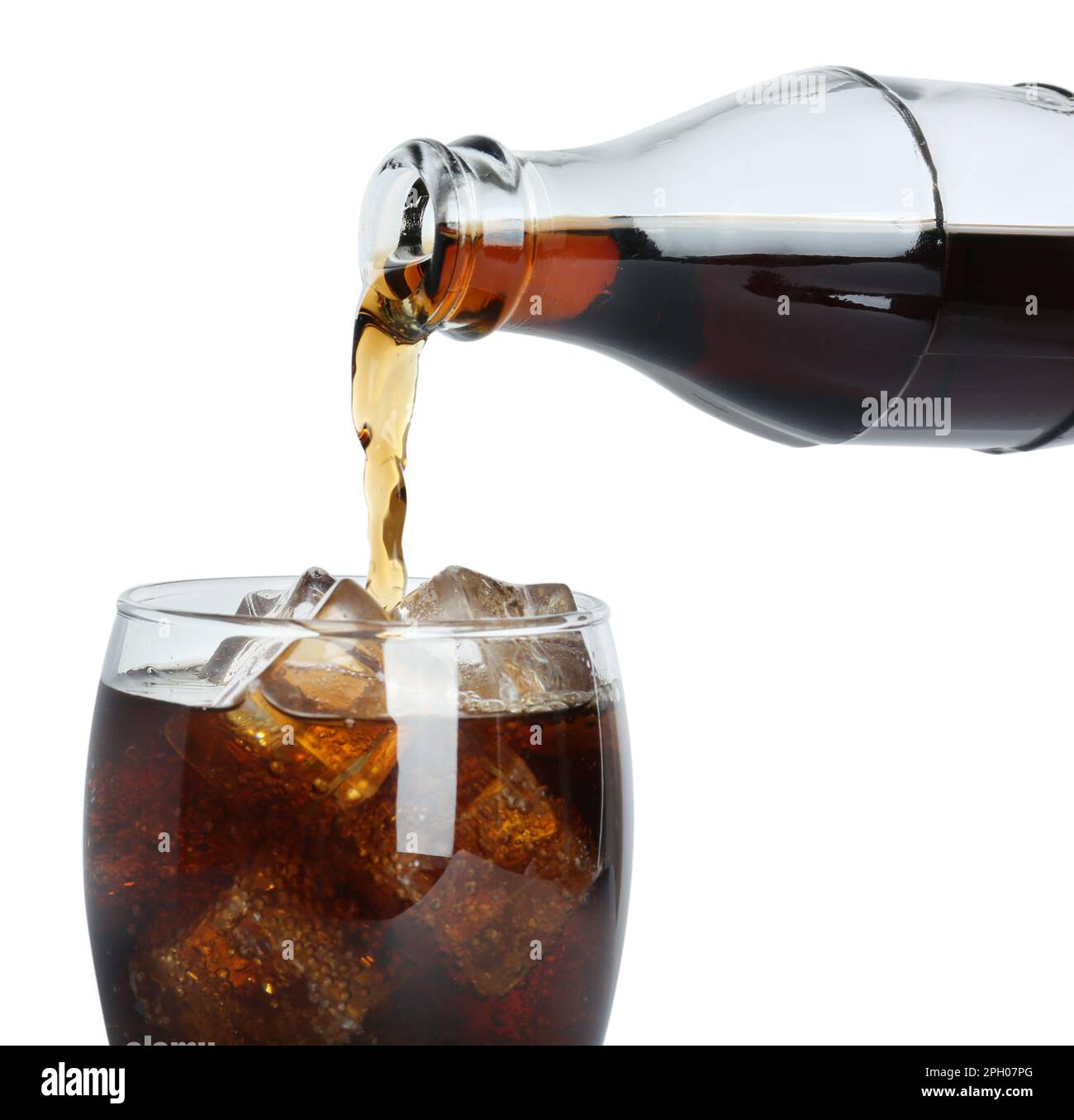 Pouring cola from bottle into glass with ice cubes on white background, closeup. Refreshing soda ...