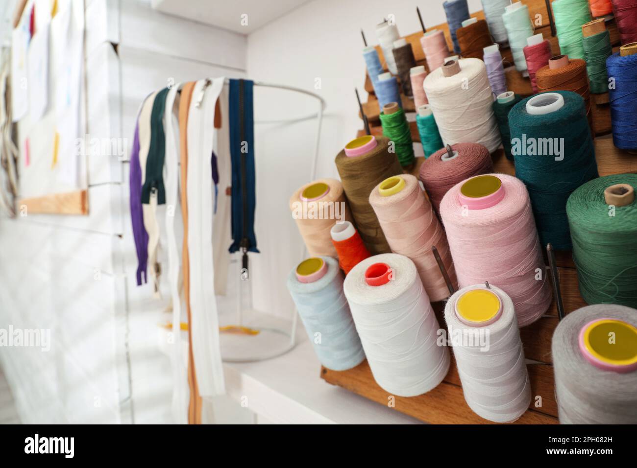 Wooden holder with collection of different threads on shelf in tailor ...