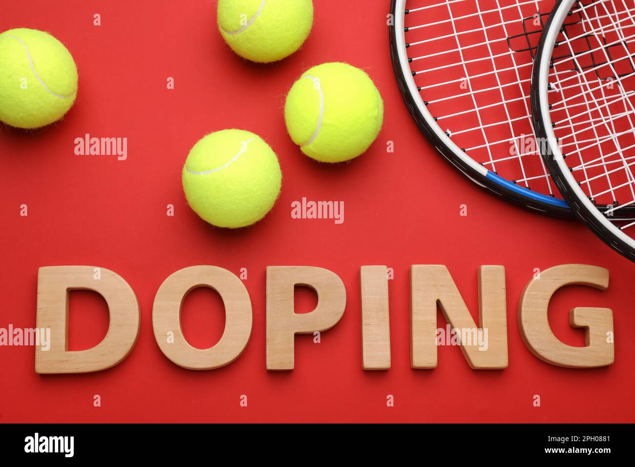 Flat lay composition with word Doping, tennis balls and rackets on red ...