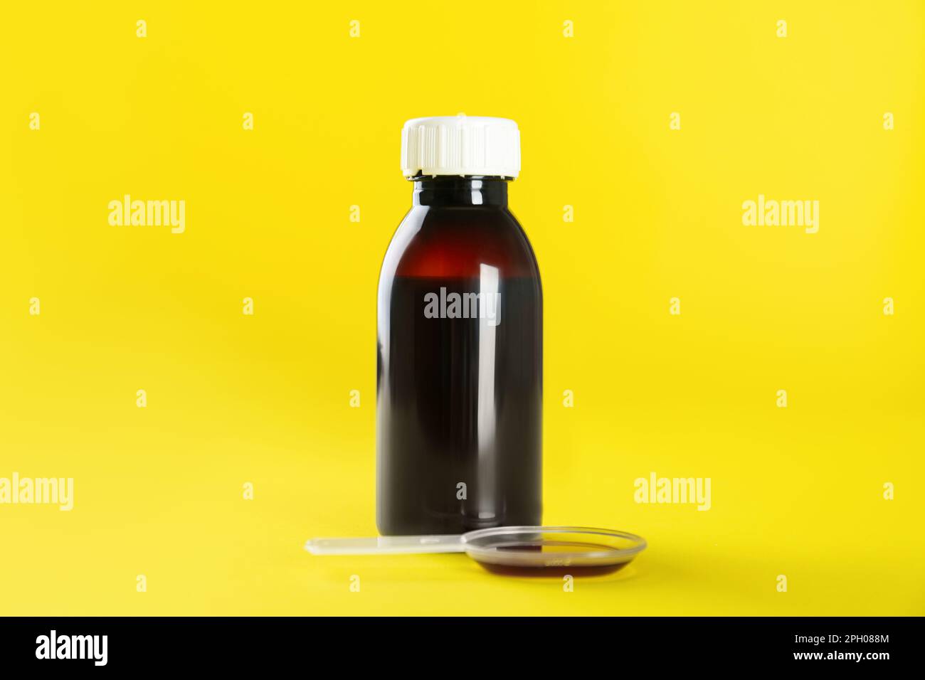 Bottle of cough syrup and dosing spoon on yellow background Stock Photo ...