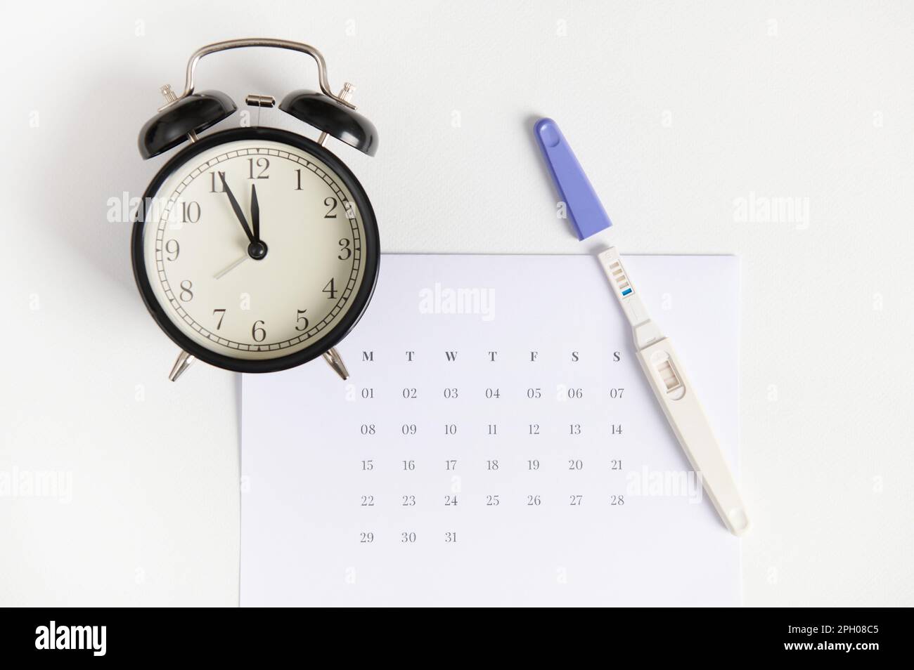Flat lay. Positive pregnancy test and alarm clock on a blank clean ...