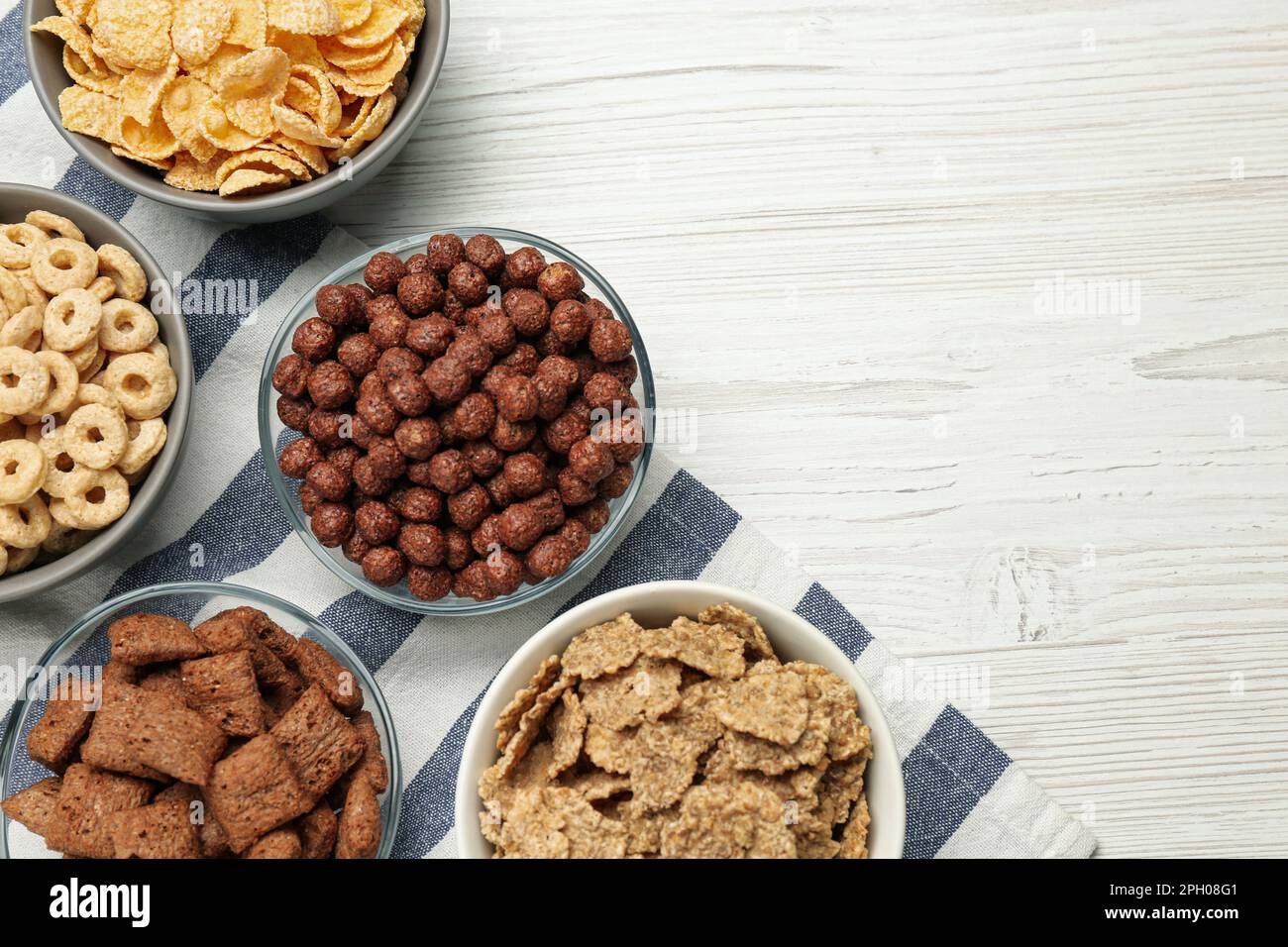 Different delicious breakfast cereals on white wooden table, top view ...