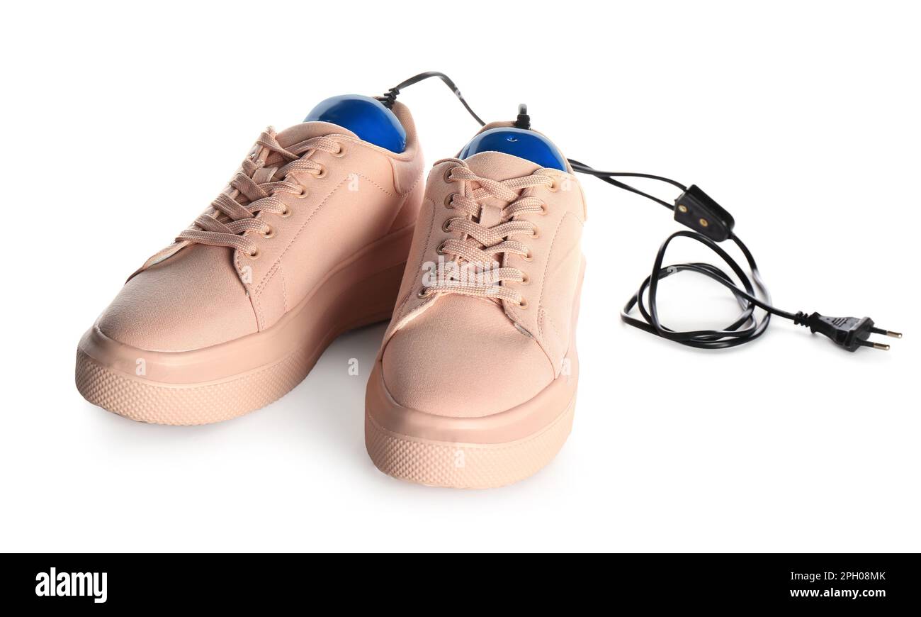 Pair of stylish shoes with modern electric footwear dryer on white ...