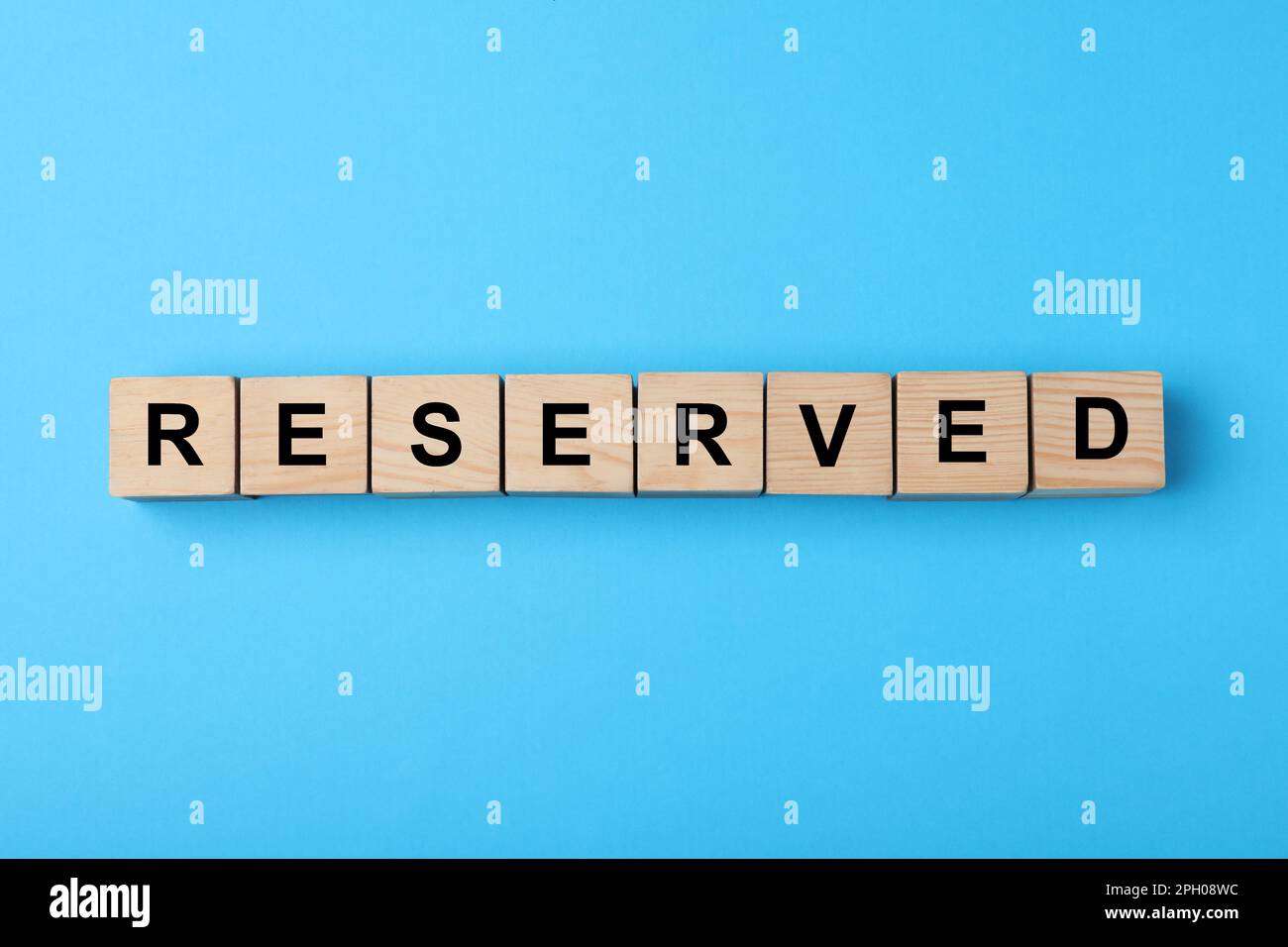 Wooden cubes with word Reserved on light blue background, flat lay ...