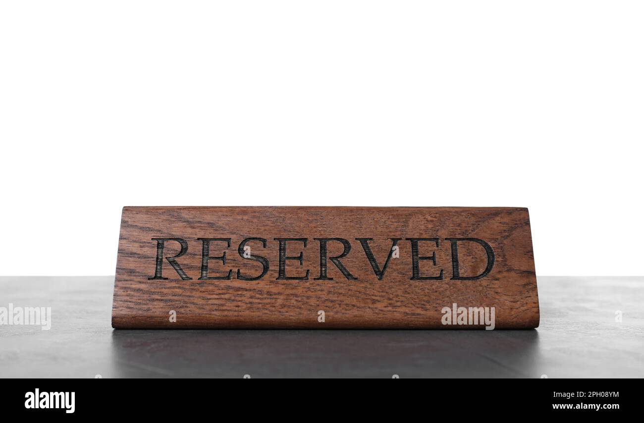 Elegant wooden sign Reserved on grey table against white background ...