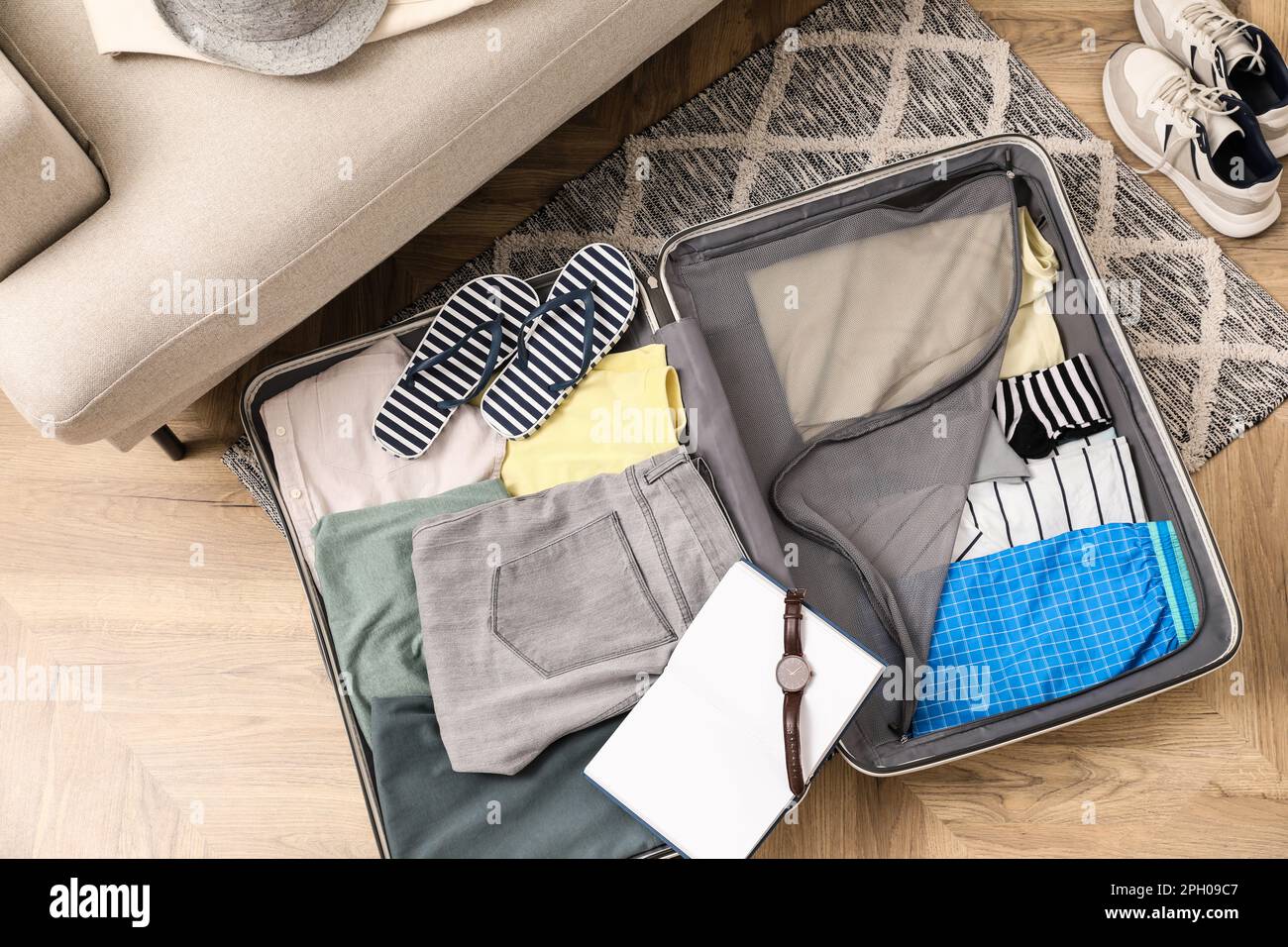 Open suitcase with different men clothes and accessories on floor, top ...