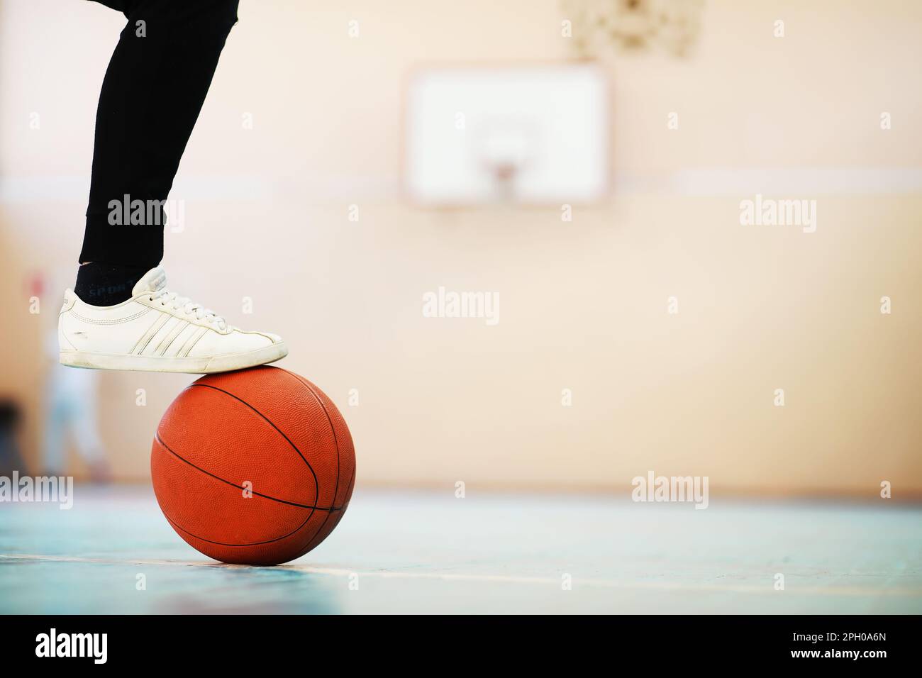 A human foot rest on the basketball on concrete floor. Photo of one ...