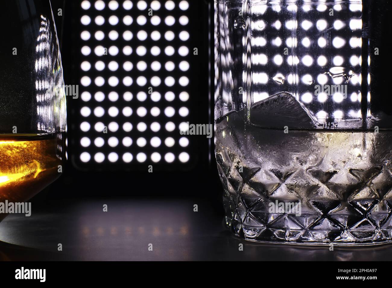 A glass of hard alcohol with ice on a bar counter. Whiskey with soda in ...