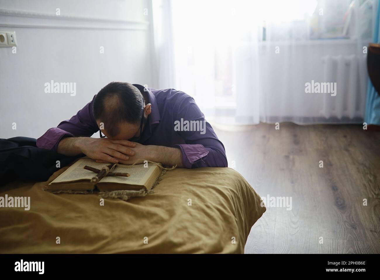 Man reading and pray from the holy bible near the bed in evening ...