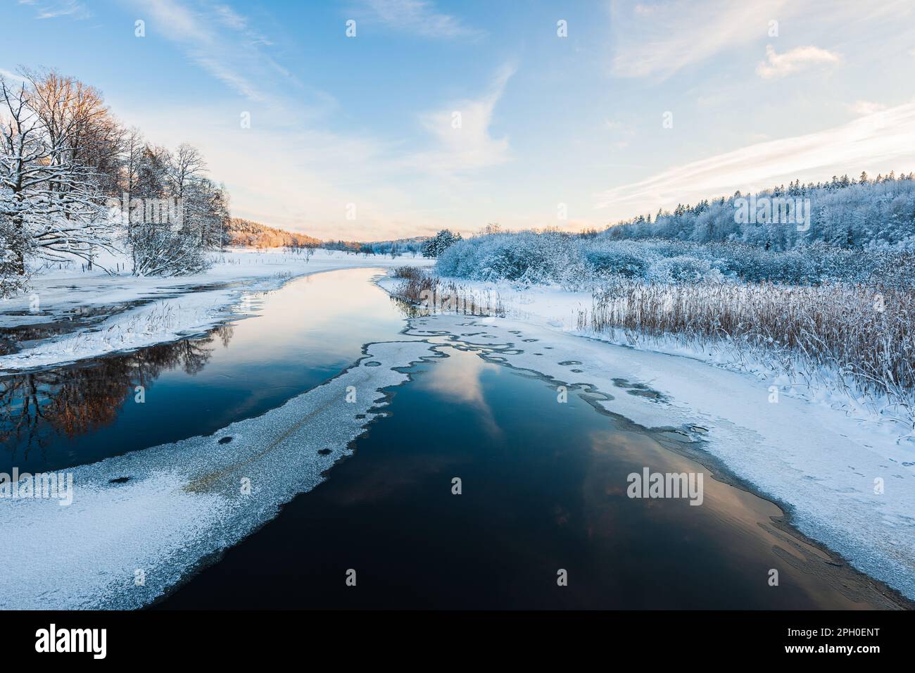 A peaceful winter morning in Sweden, with a frozen river snaking ...