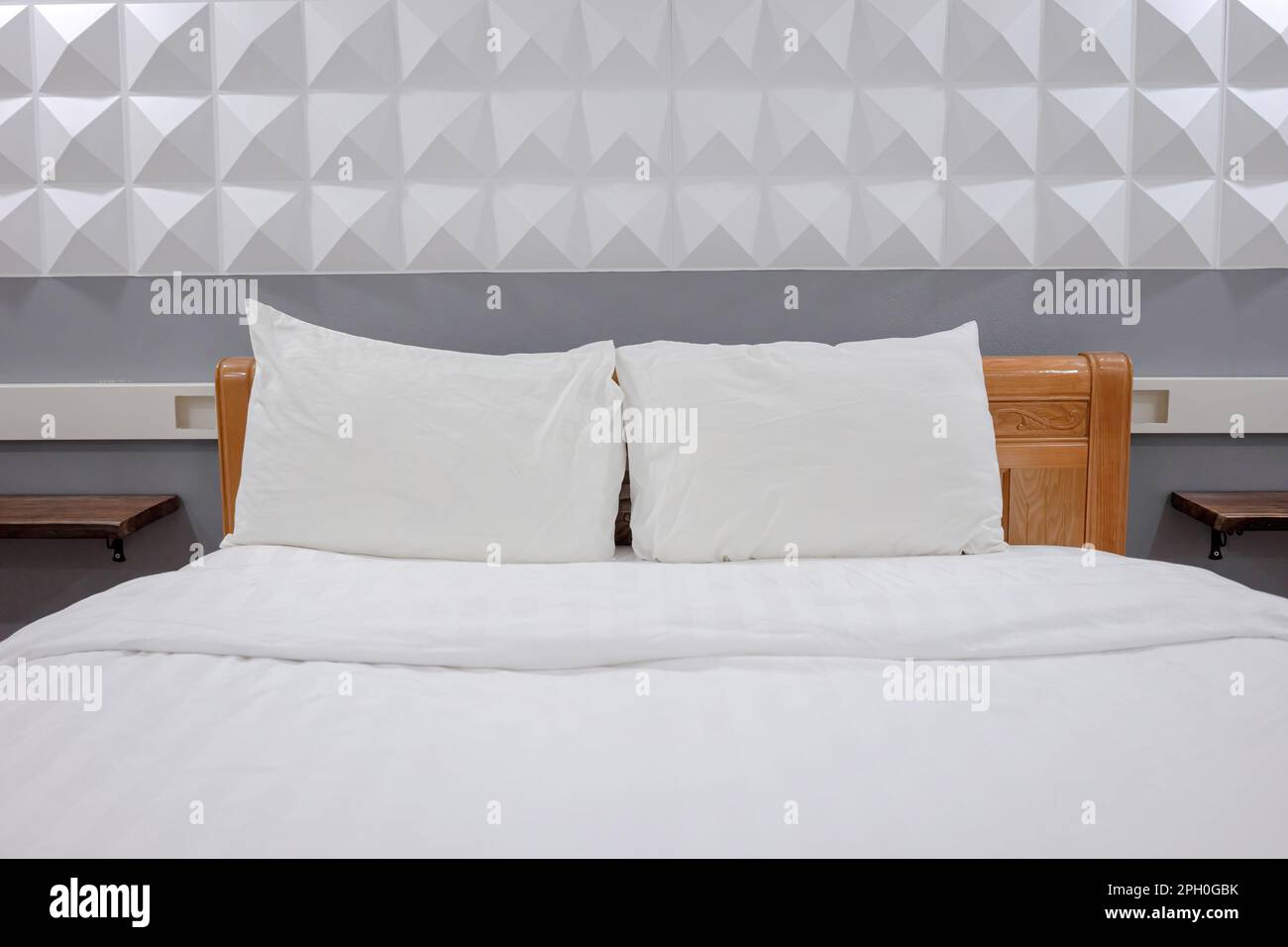View of a bed with a white duvet cover and two pillows in front of a ...