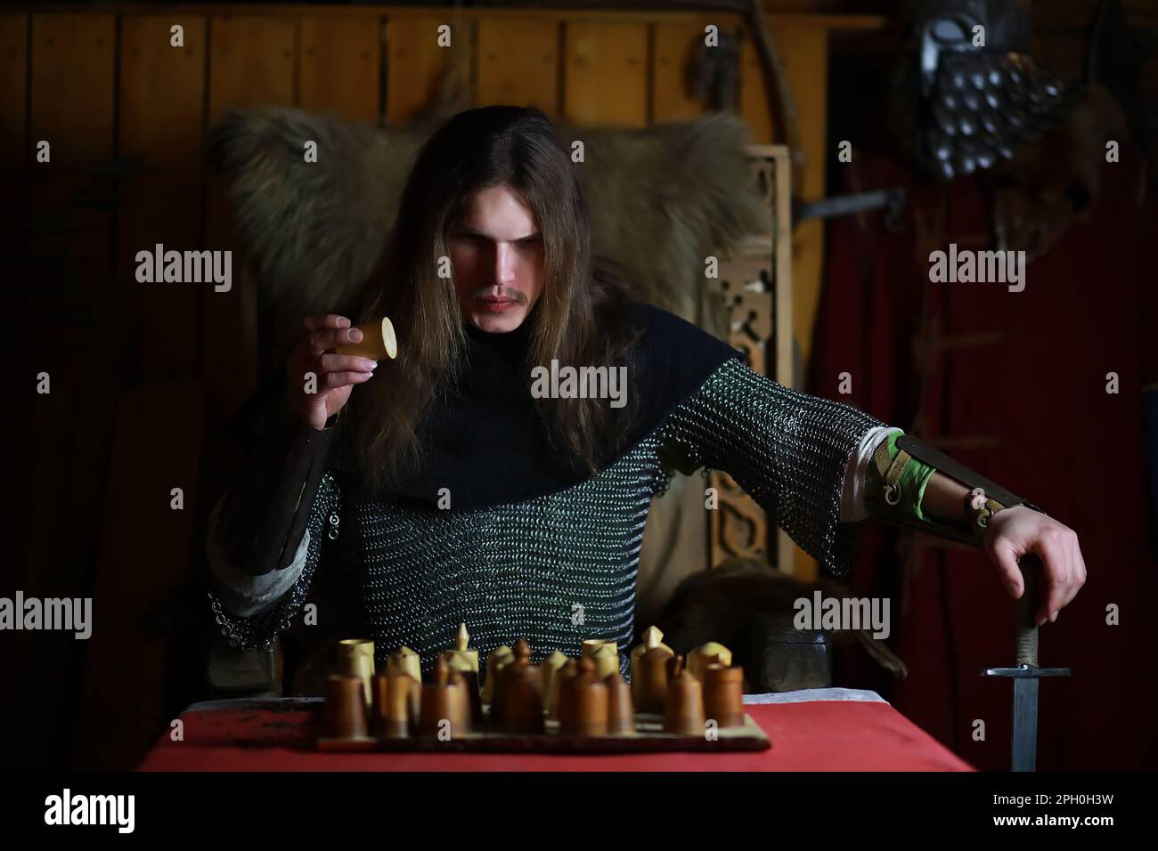 A mighty hero with long hair in chain mail armor in an ancient hall ...