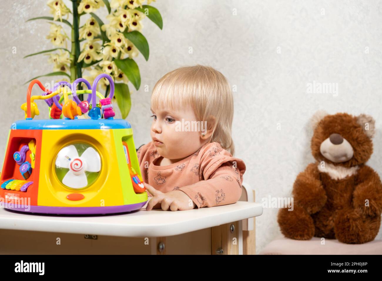 A one-and-a-half-year-old girl plays with a musical glowing toy ...