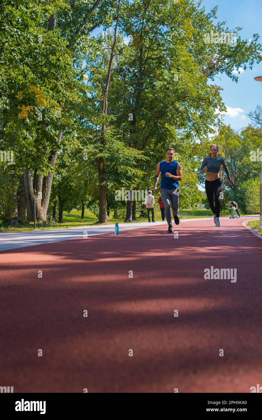 Two adult fitness models running in the park Stock Photo - Alamy