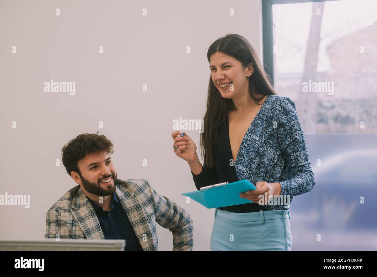 Two good looking business colleagues smiling together while working at ...