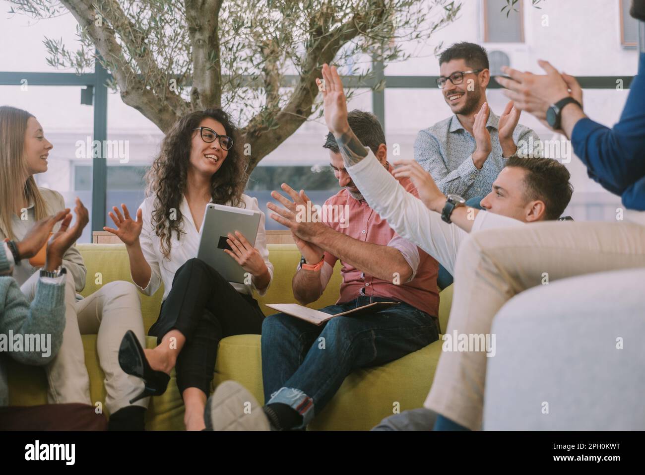 Group of successful business workers cheering together while sitting at ...
