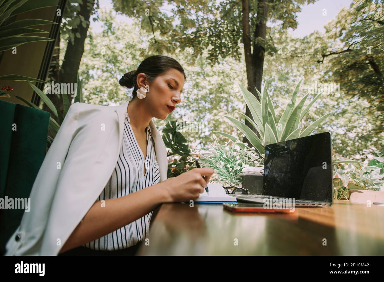 Amazing business woman writting notes on the notebook while sitting at ...