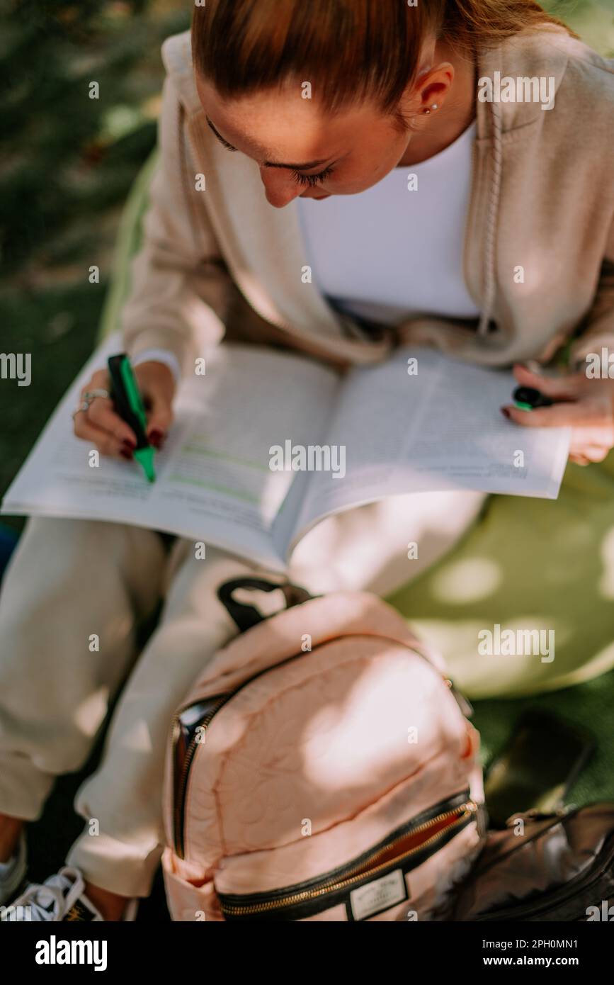 High school girl is underlining important parts in the book with a ...