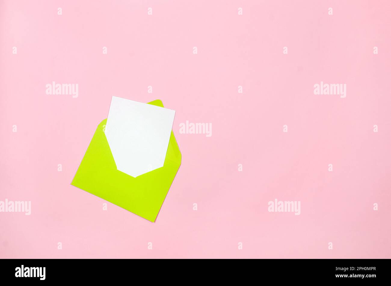 light green envelope with blank card on pastel pink background ...