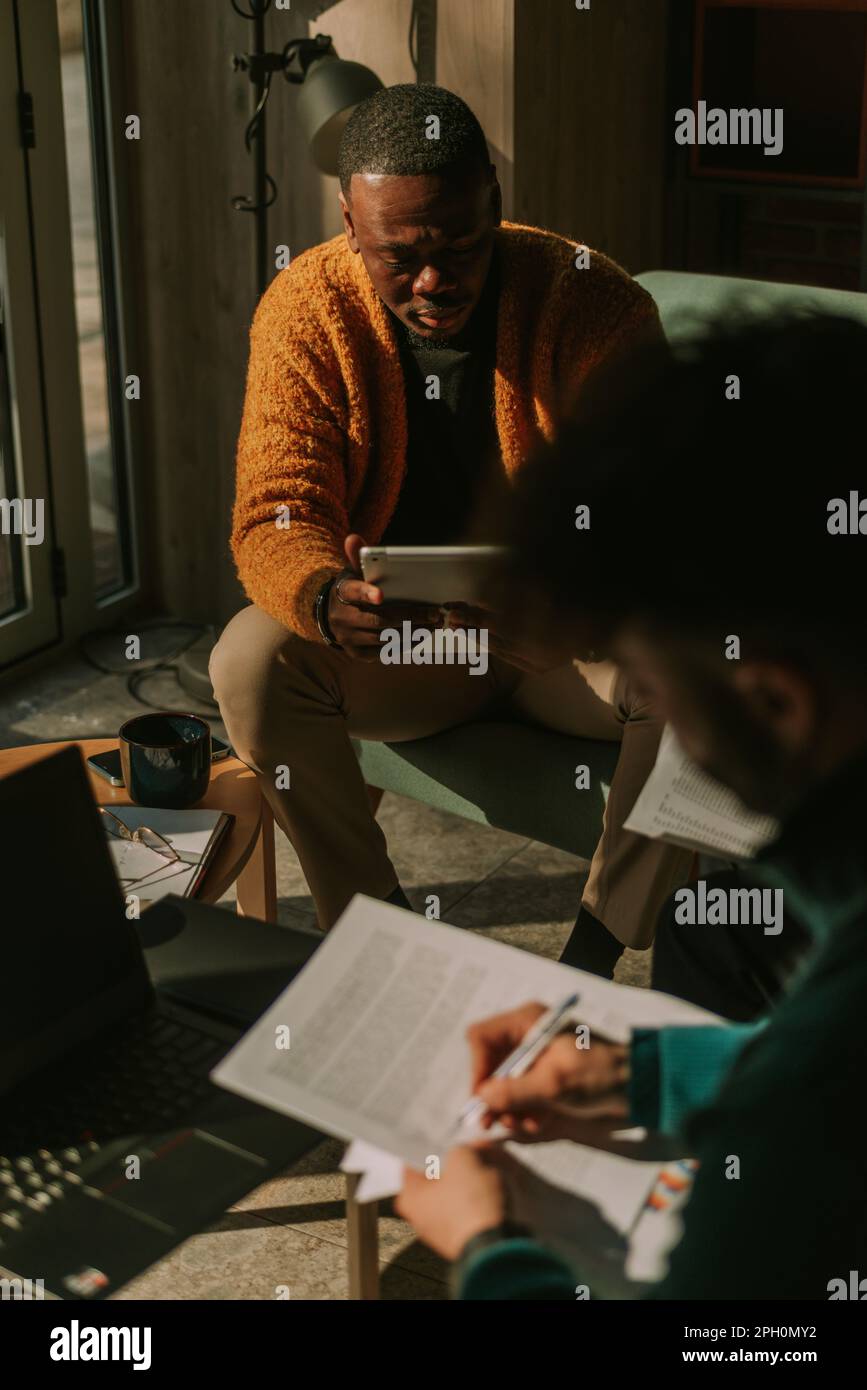 A photo of stylish handsome black person working on the tablet while ...
