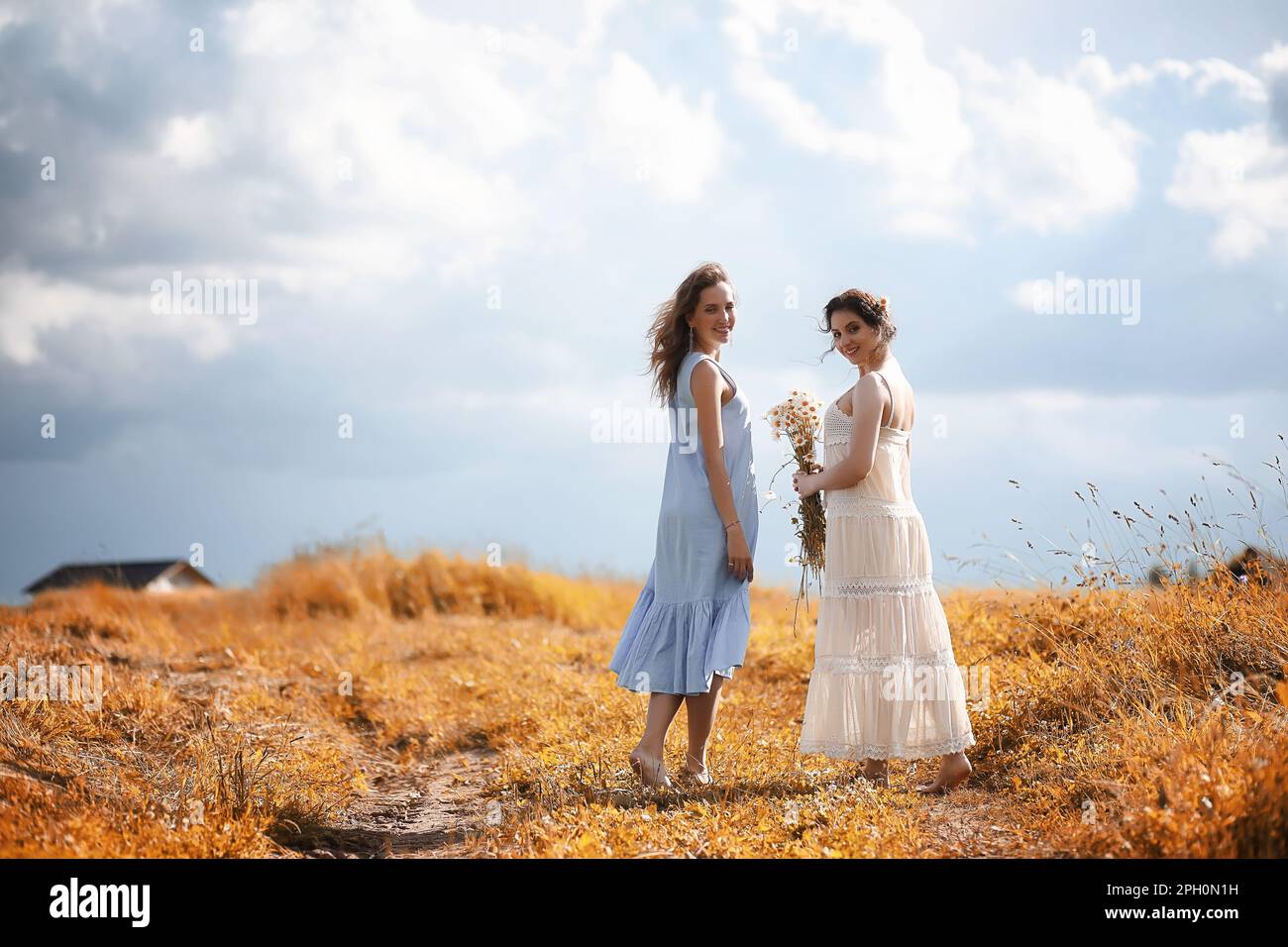 Two beautiful girls in dresses in autumn field have fun Stock Photo - Alamy