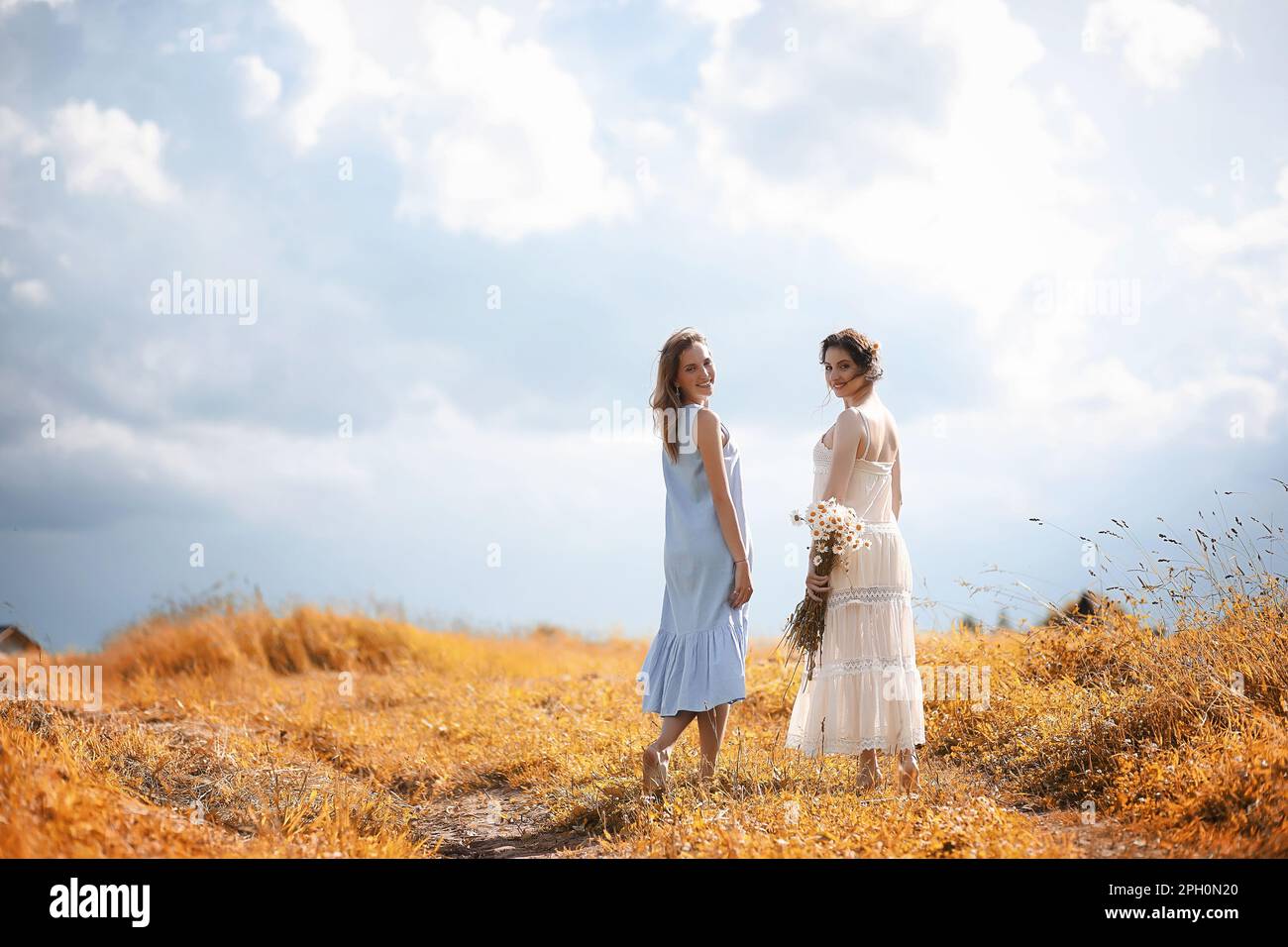Two beautiful girls in dresses in autumn field have fun Stock Photo - Alamy