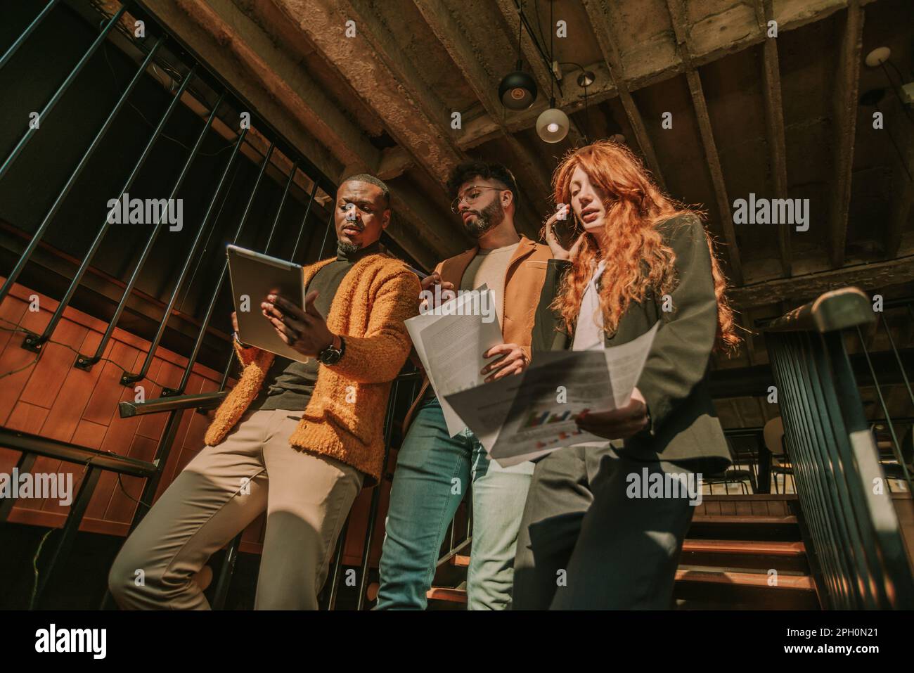 Gorgeous redhead businesswoman having a phone call while her two male ...