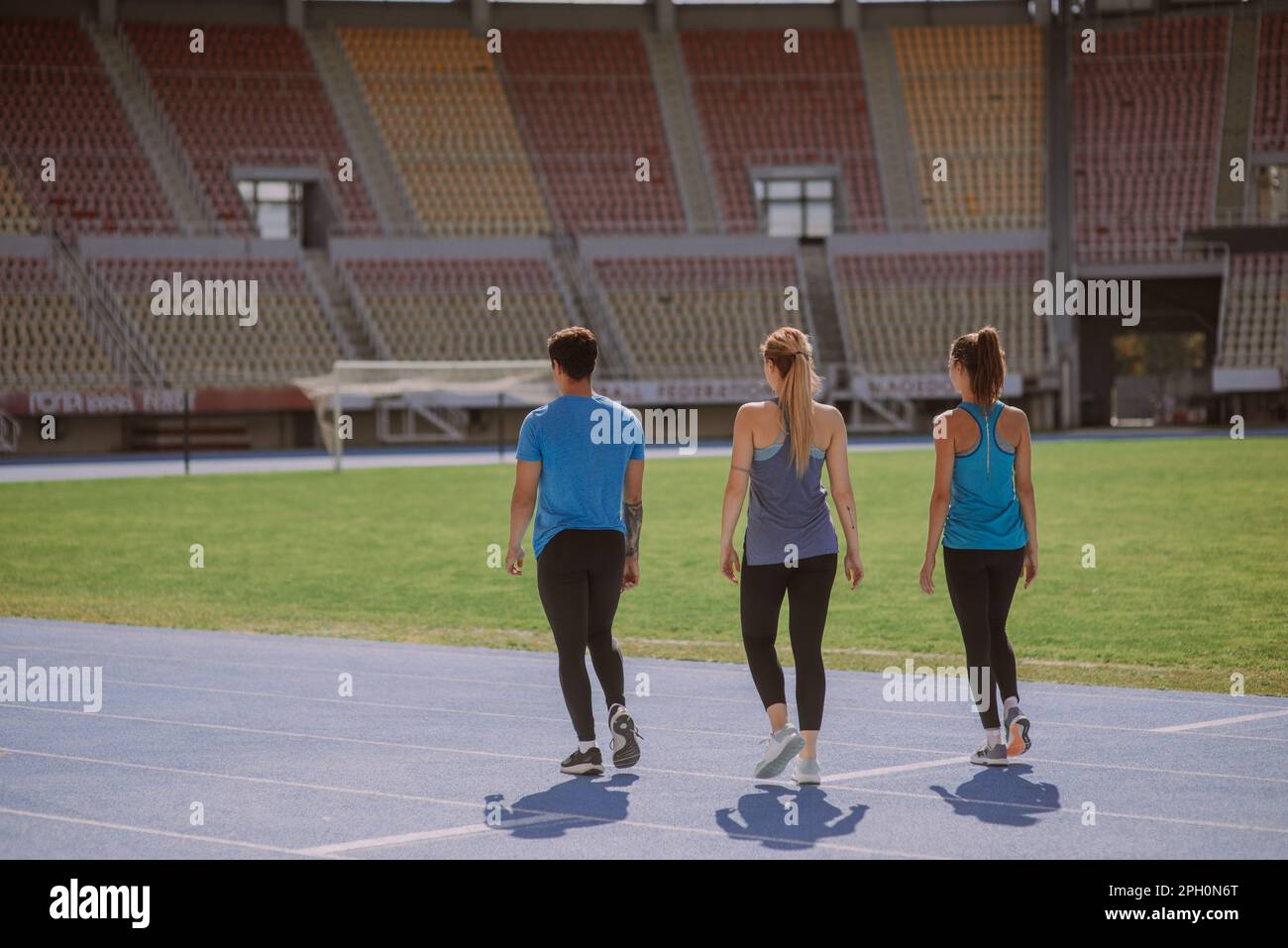 Three sporty friends are walking on the sports track, after running ...