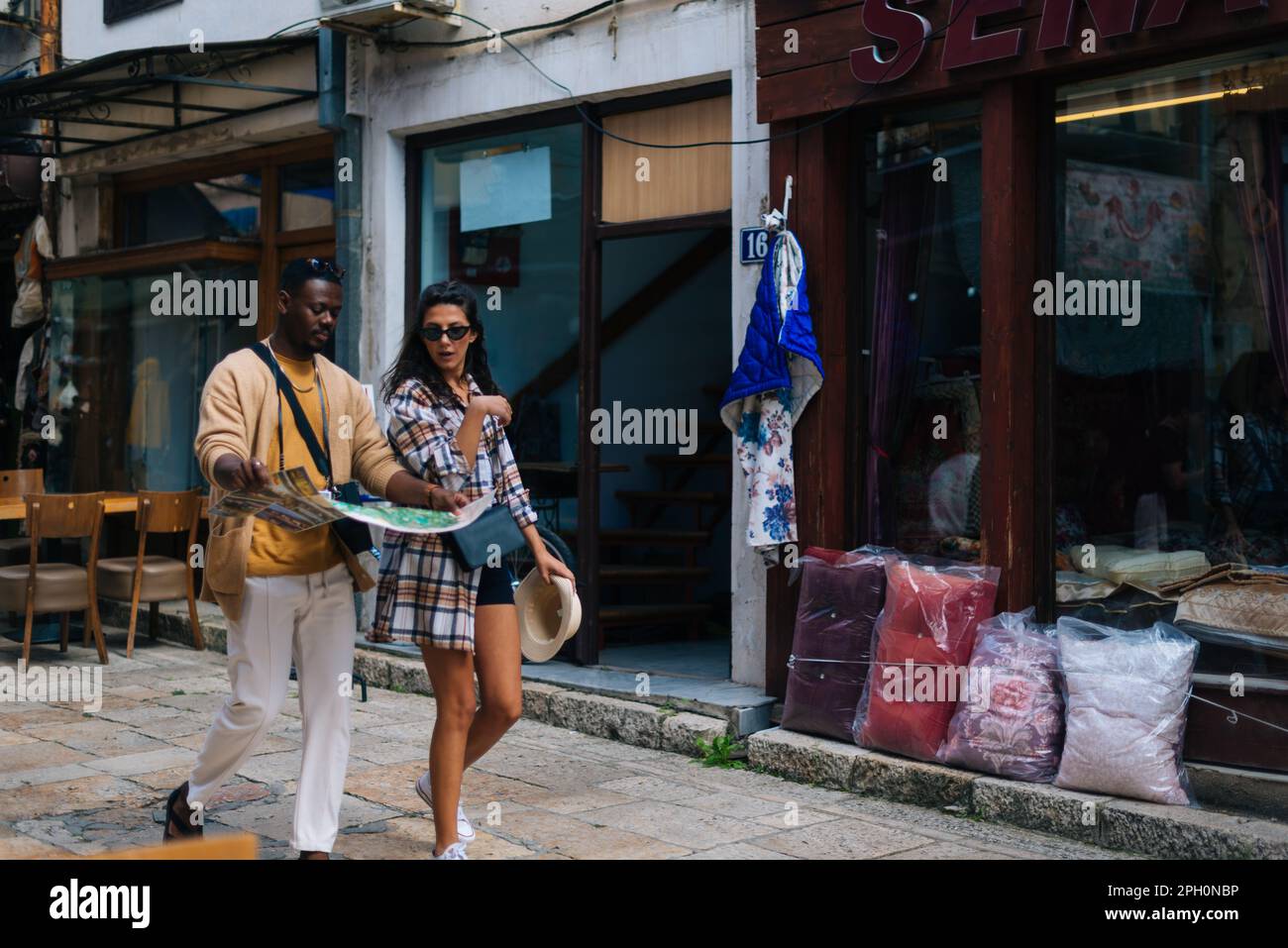 Two multiracial tourists are hanging out in the city, carrying a map ...
