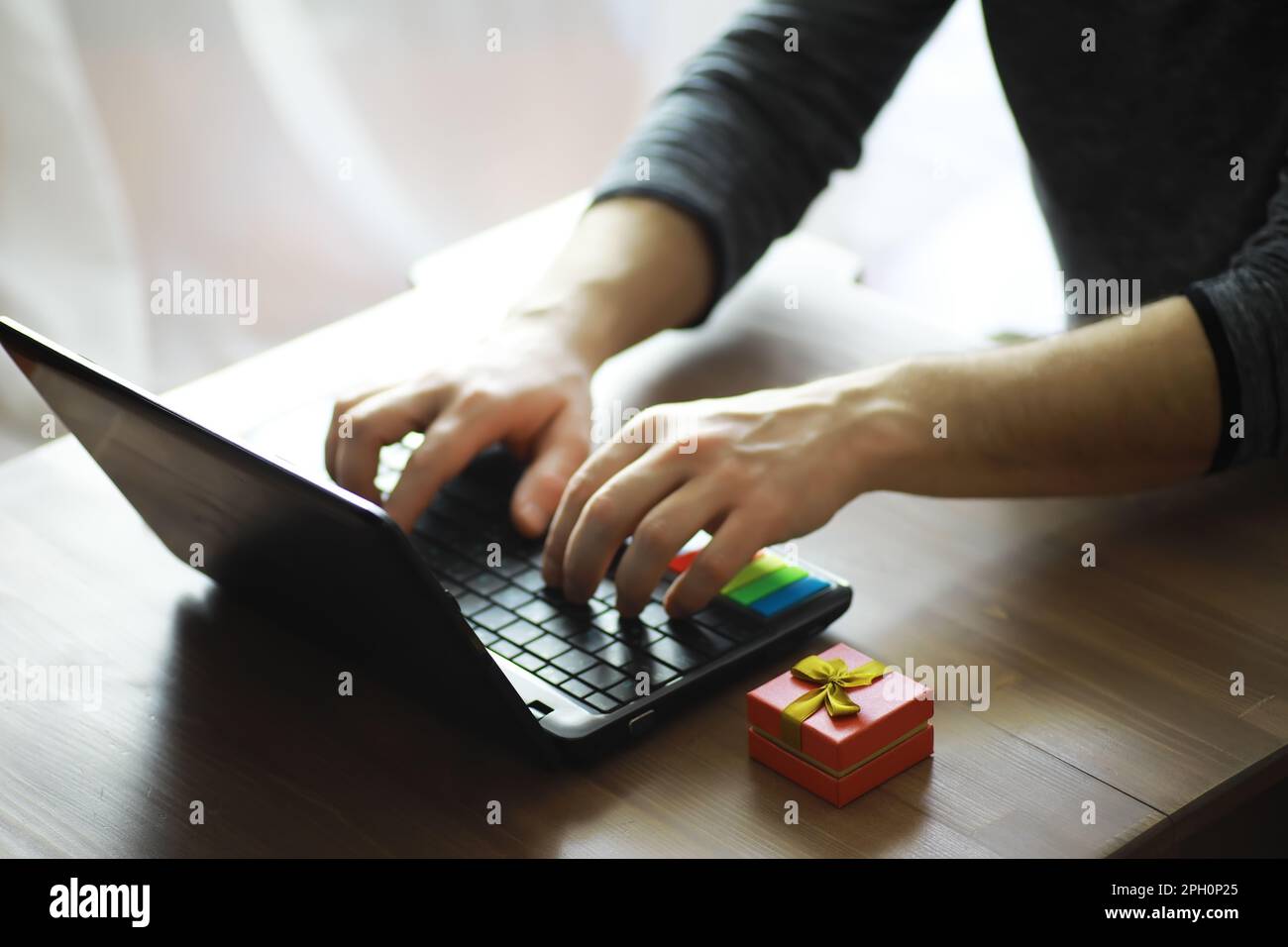 A man with a gift in his hand sits in front of the monitor screen ...