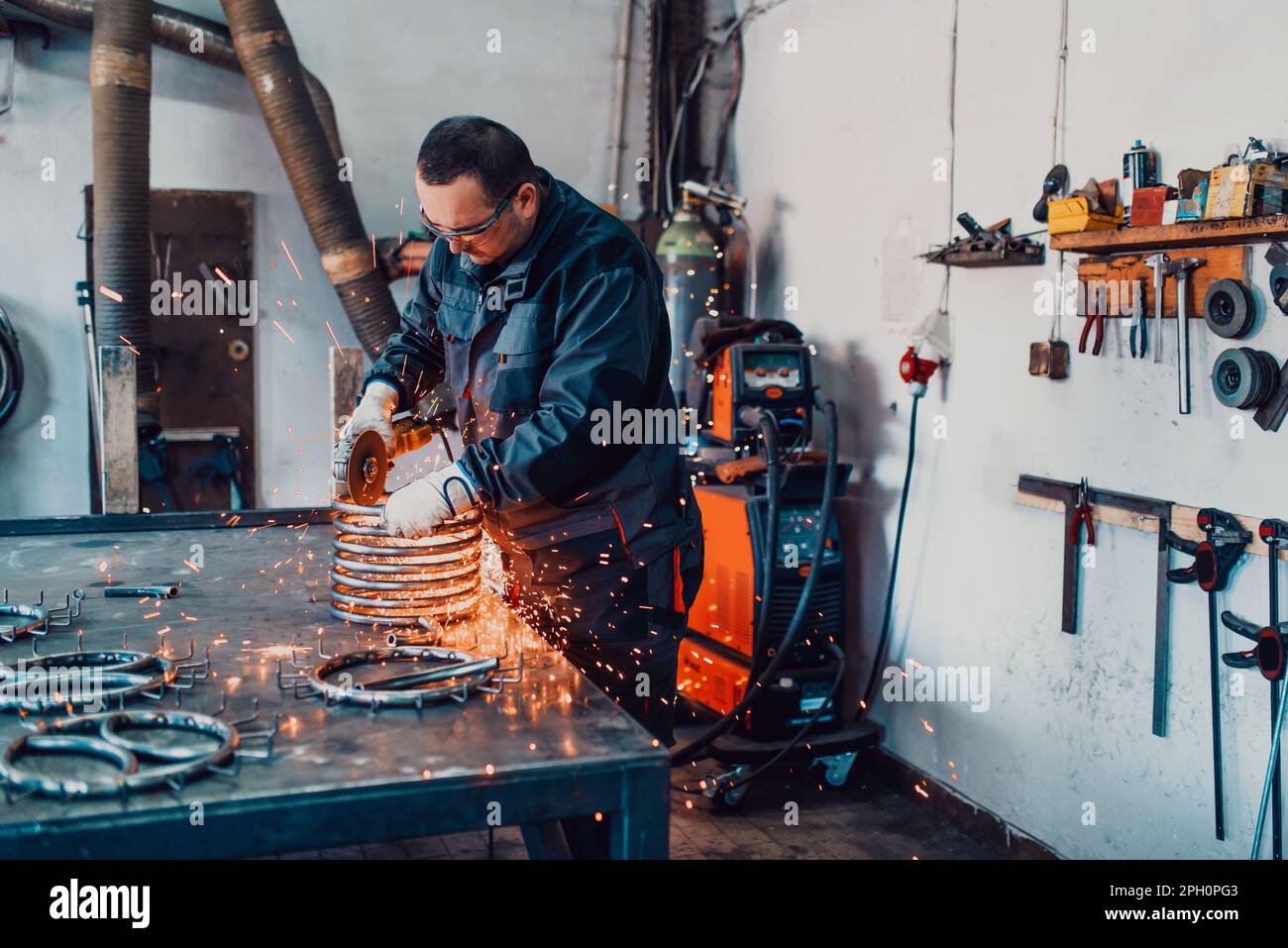 Locksmith in special clothes and goggles works in production. Metal ...