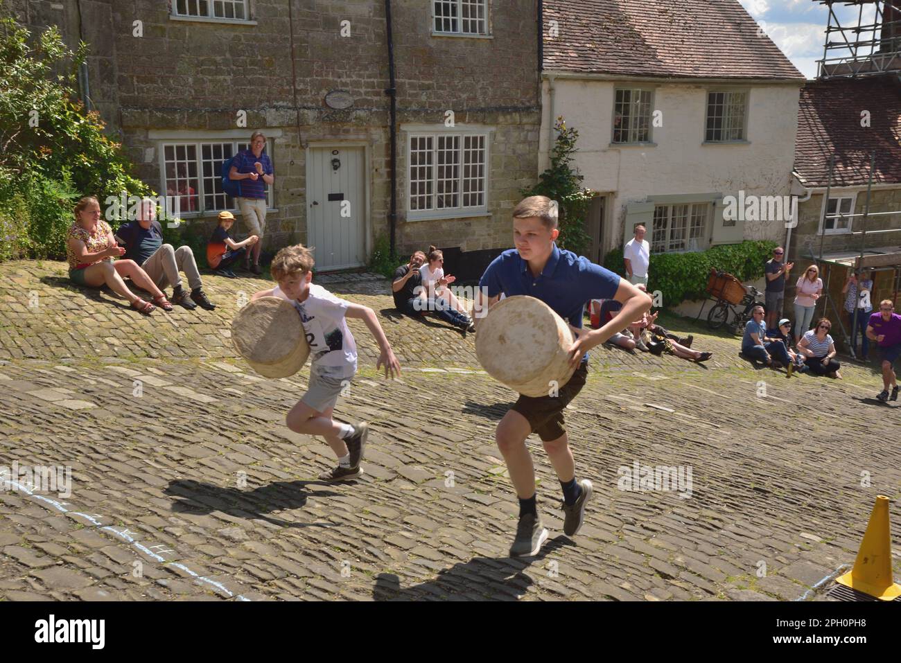 Two boys carry their "cheeses" in the cheese race running up Gold Hill ...