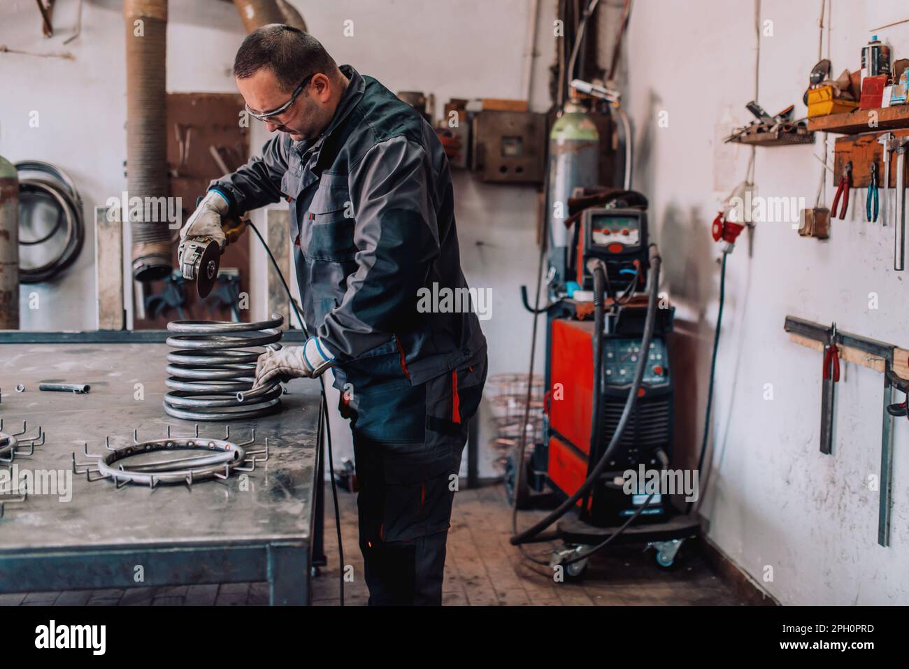 Locksmith in special clothes and goggles works in production. Metal ...
