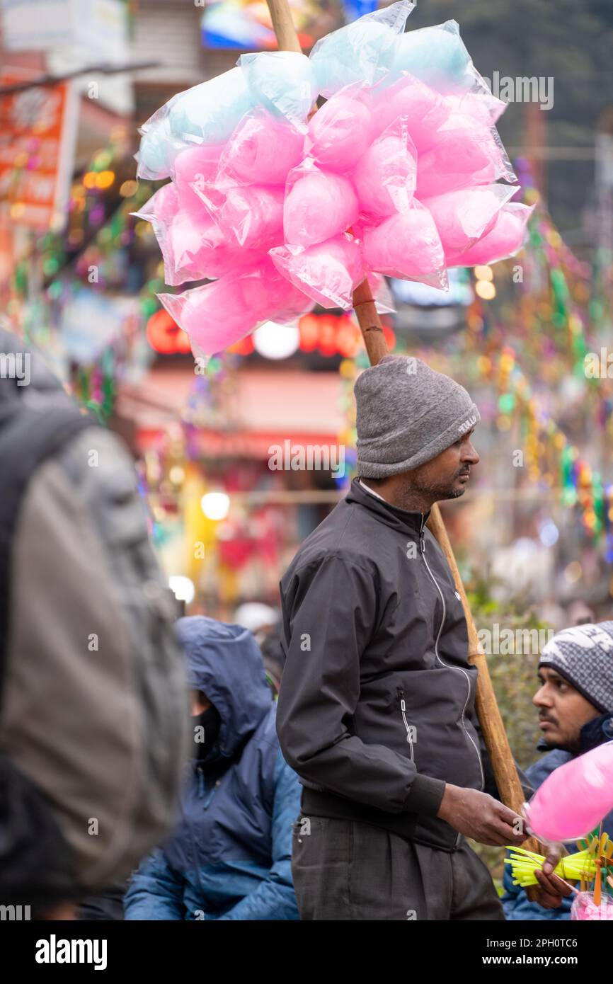 Man selling cotton candy being sold in small poly bags mounted on a ...