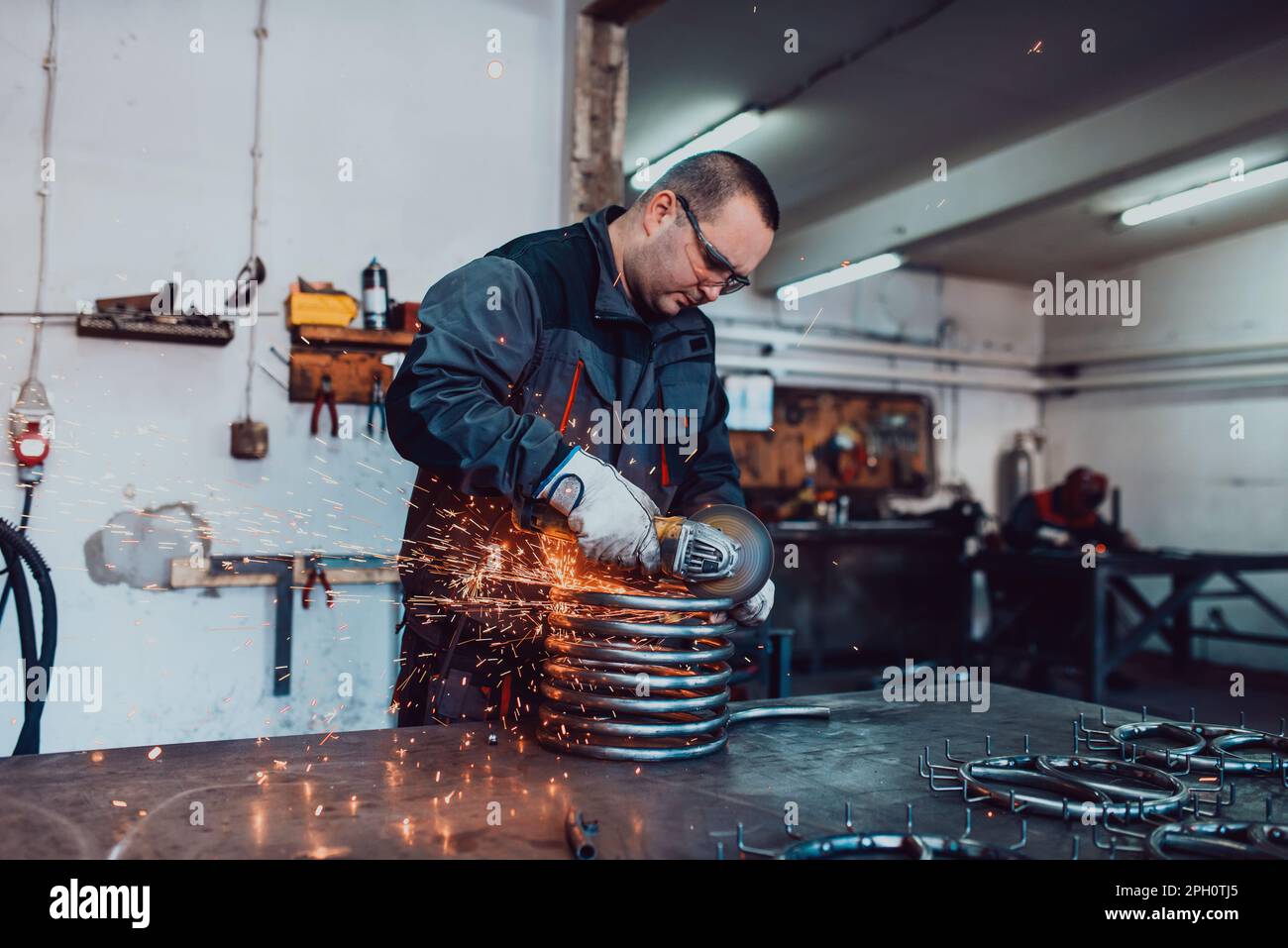 Locksmith in special clothes and goggles works in production. Metal ...