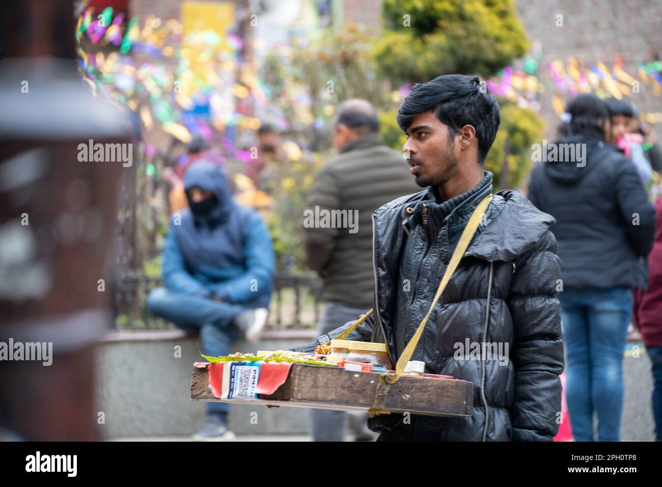 Snack vendor with tray of street food around his neck looking for ...