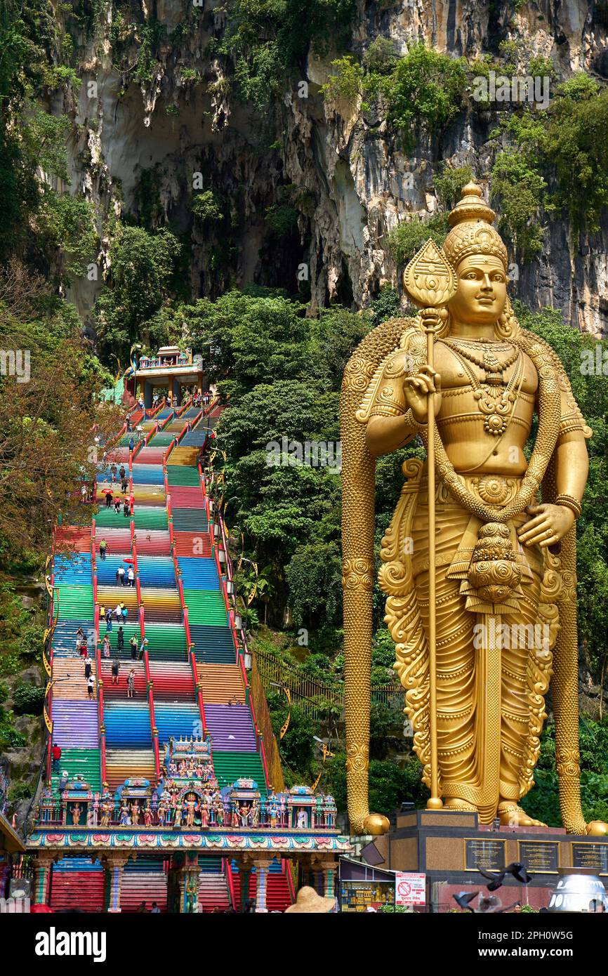 A huge golden statue of Lord Murugan at the entrance with multicolored ...