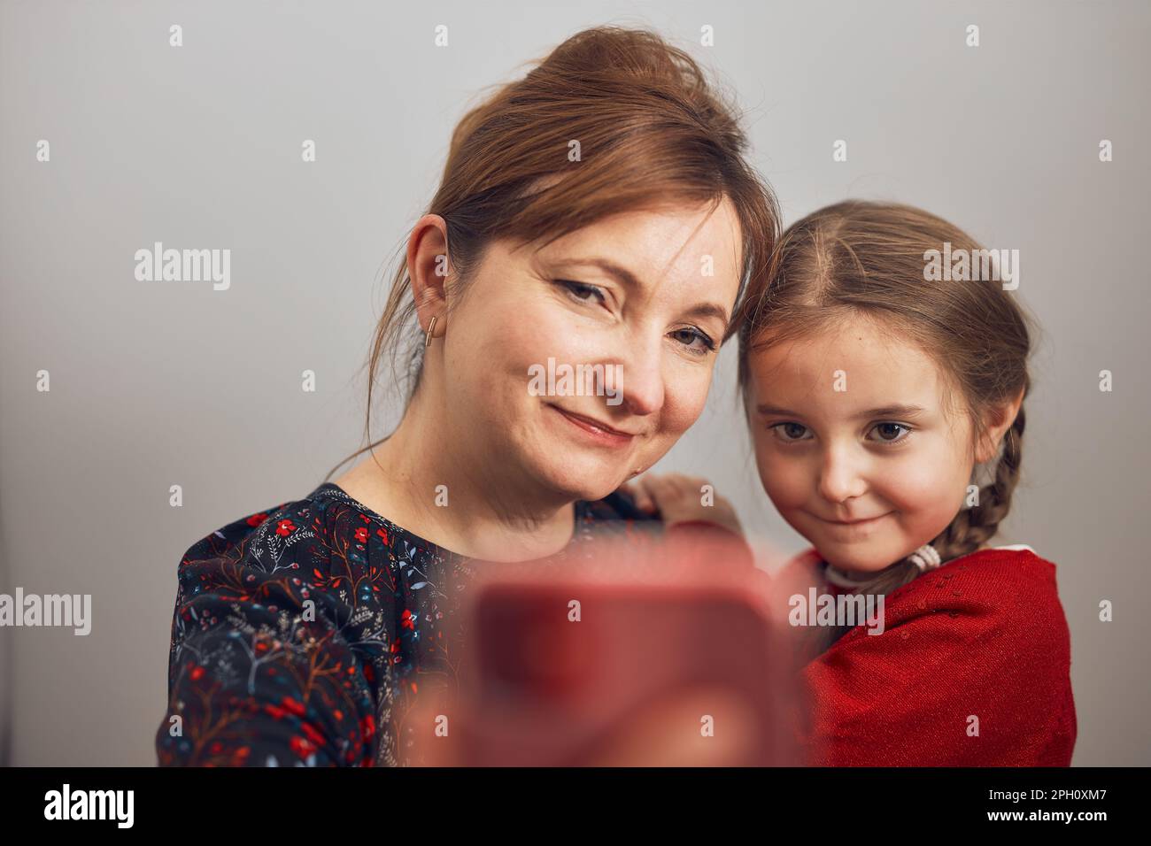 Mother with her little daughter making video call using mobile phone ...