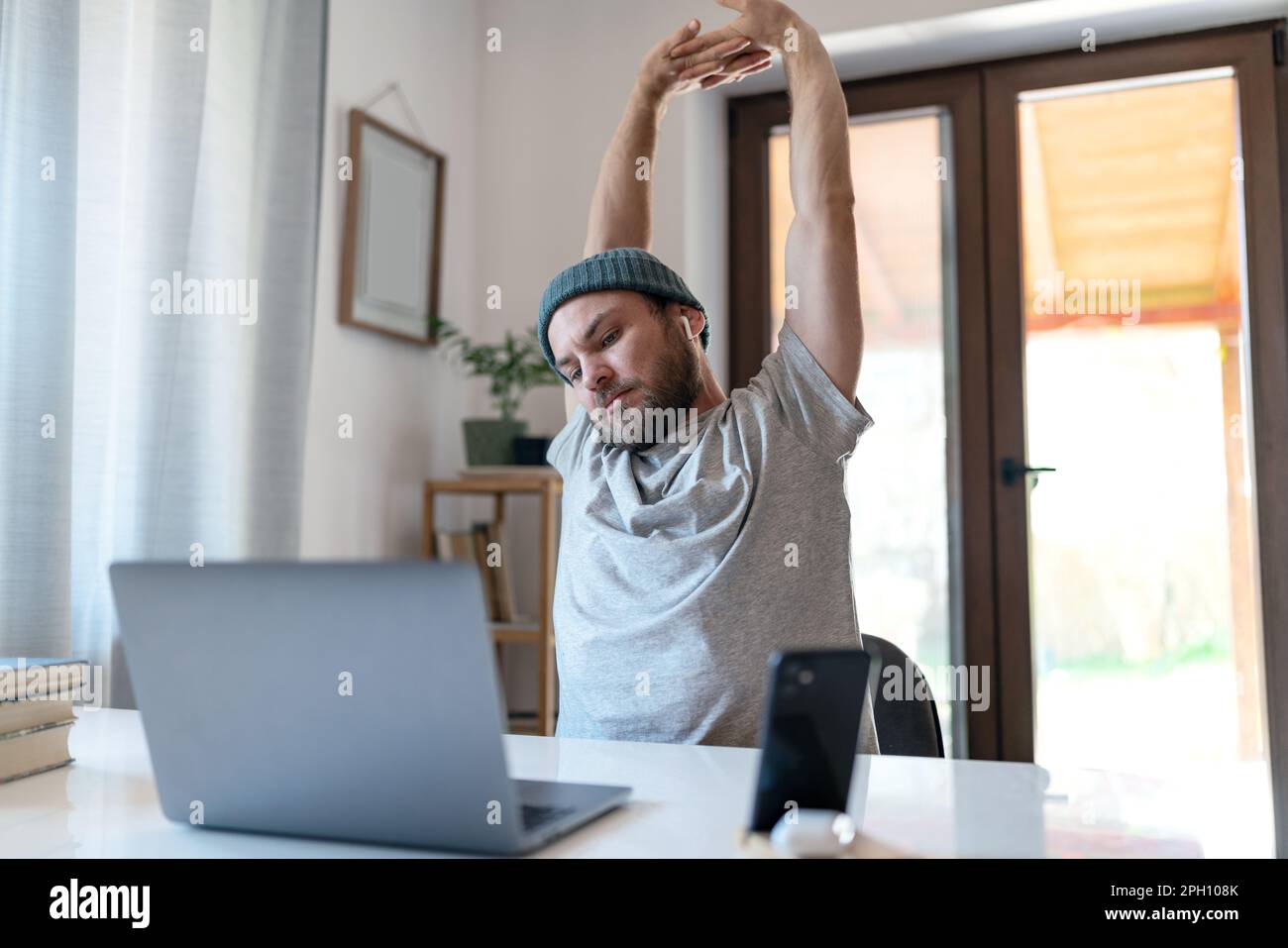 Man stretching his body while working on laptop from home Stock Photo ...
