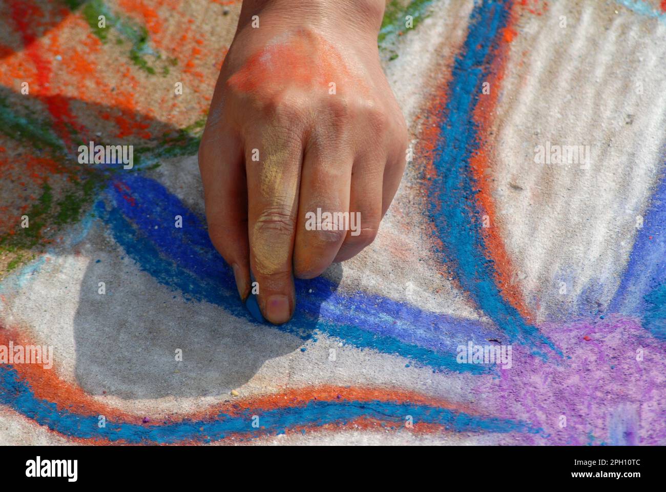 An artist hand at work making beautiful works of art on the street ...