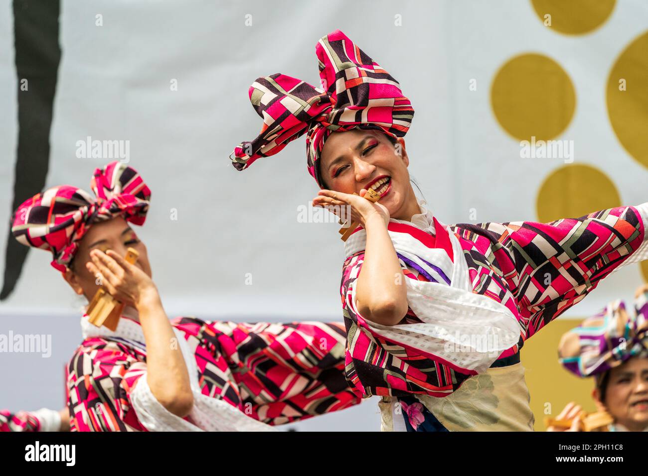 Close up of two young Japanese women dancers wearing colourful headscarves on an outdoor stage ...