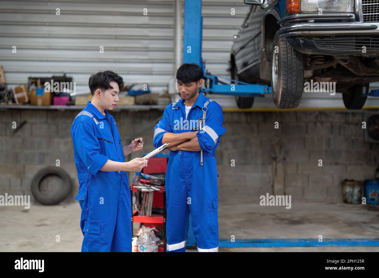 Mechanic man shows report to the asian coworker at garage, A man ...