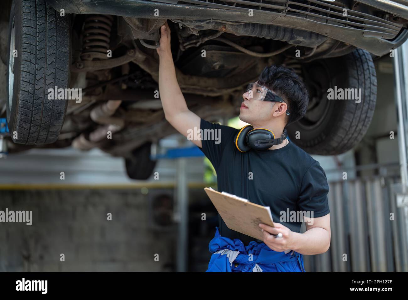 Vehicle service maintenance asian man checking under car condition in ...